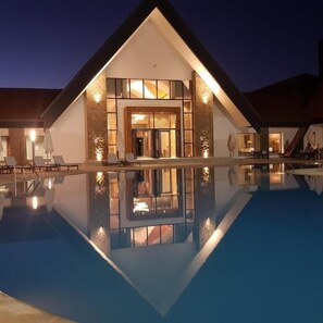 Hotel moderno com uma piscina grande, refletindo a arquitetura do edifício.