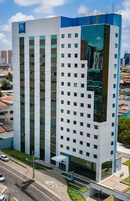 Um hotel moderno com fachada de vidro destacada, vários andares e esquema de cores azul e branco.
