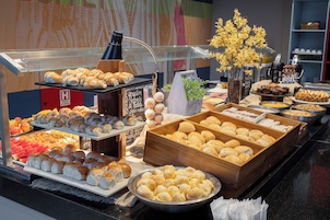 Exposição de uma padaria com diversos produtos de panificação, incluindo doces e pães, dispostos em prateleiras e recipientes.