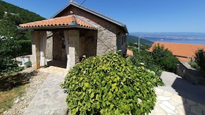 Um edifício de pedra com telhado em telhas, um letreiro de boas-vindas e vista para a paisagem costeira.