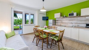 Cozinha moderna com armários brancos, parede verde e área de jantar com mesa e cadeiras de madeira.