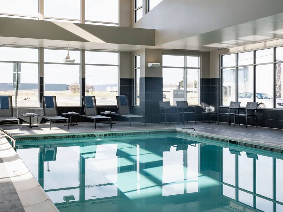 Uma área de piscina com vista desobstruída para o exterior, incluindo um parque de estacionamento e um edifício com a inscrição 'Residence'.