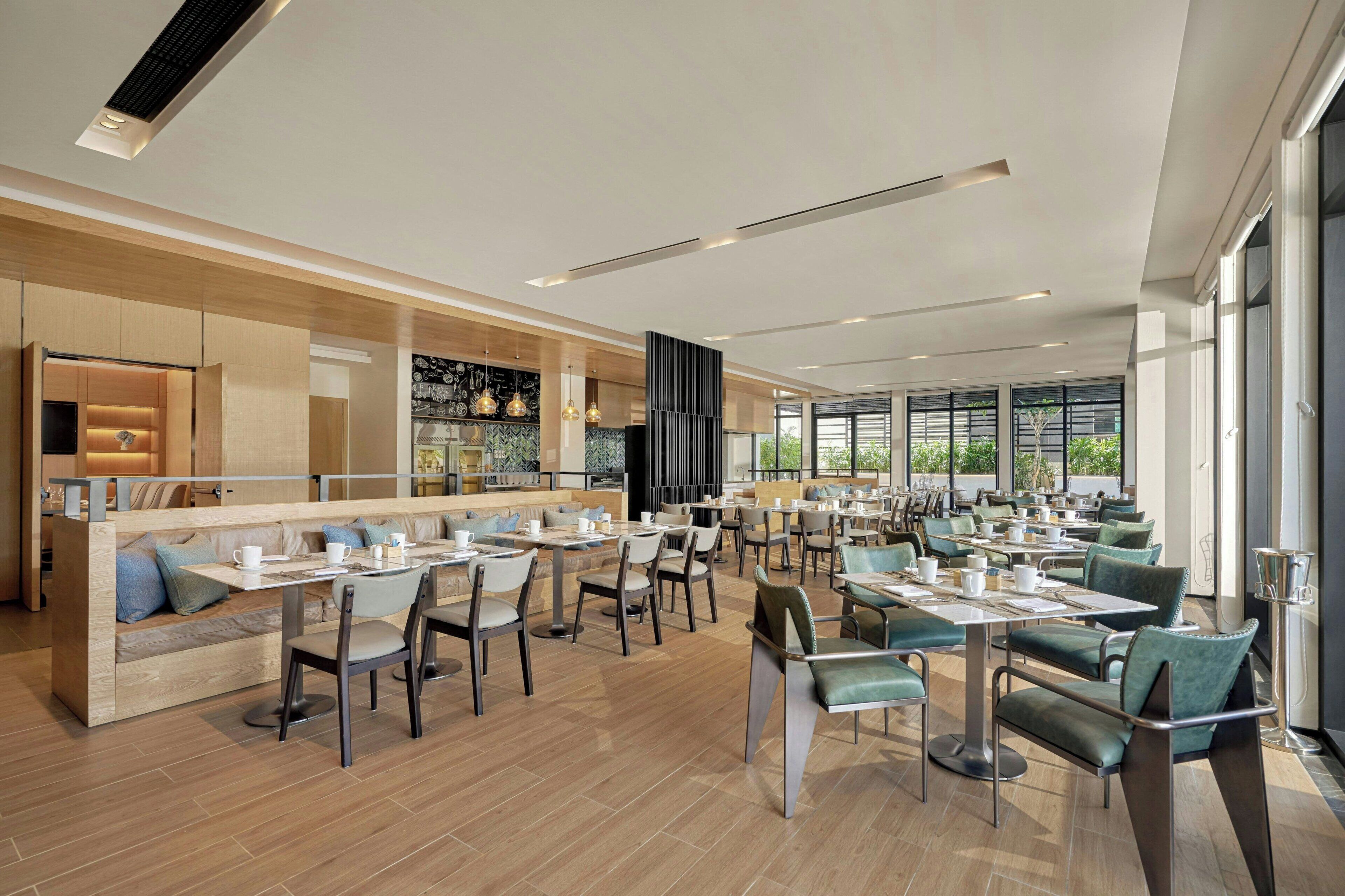 Um restaurante espaçoso com diversas áreas de estar, incluindo cabines e mesas, e amplas janelas que proporcionam luz natural.