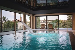 Piscina interna com água cristalina, uma fonte e espreguiçadeiras.