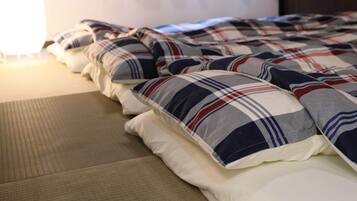 Cama bem arrumada com roupa de cama xadrez e travesseiro branco.