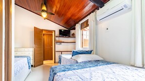Quarto com duas camas, televisão e ar condicionado.