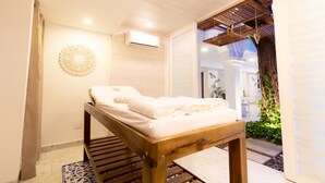 Quarto com um banco de madeira, um colchão branco e um objeto decorativo na parede.