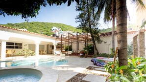 Área de piscina com hidromassagem, espreguiçadeiras e um pergolado.