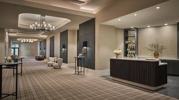 Um lobby de hotel moderno com área de bar, assentos e balcão de recepção.