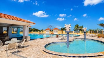 Piscina com fonte, espreguiçadeiras e área de estar coberta.