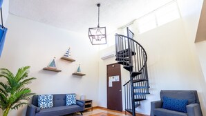 Uma sala de estar com sofá, poltrona e escada em espiral.