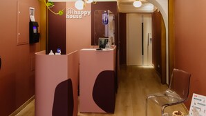 Uma área de recepção com design moderno, incluindo um balcão de atendimento, um quiosque de informações digitais e uma cadeira de vidro transparente.