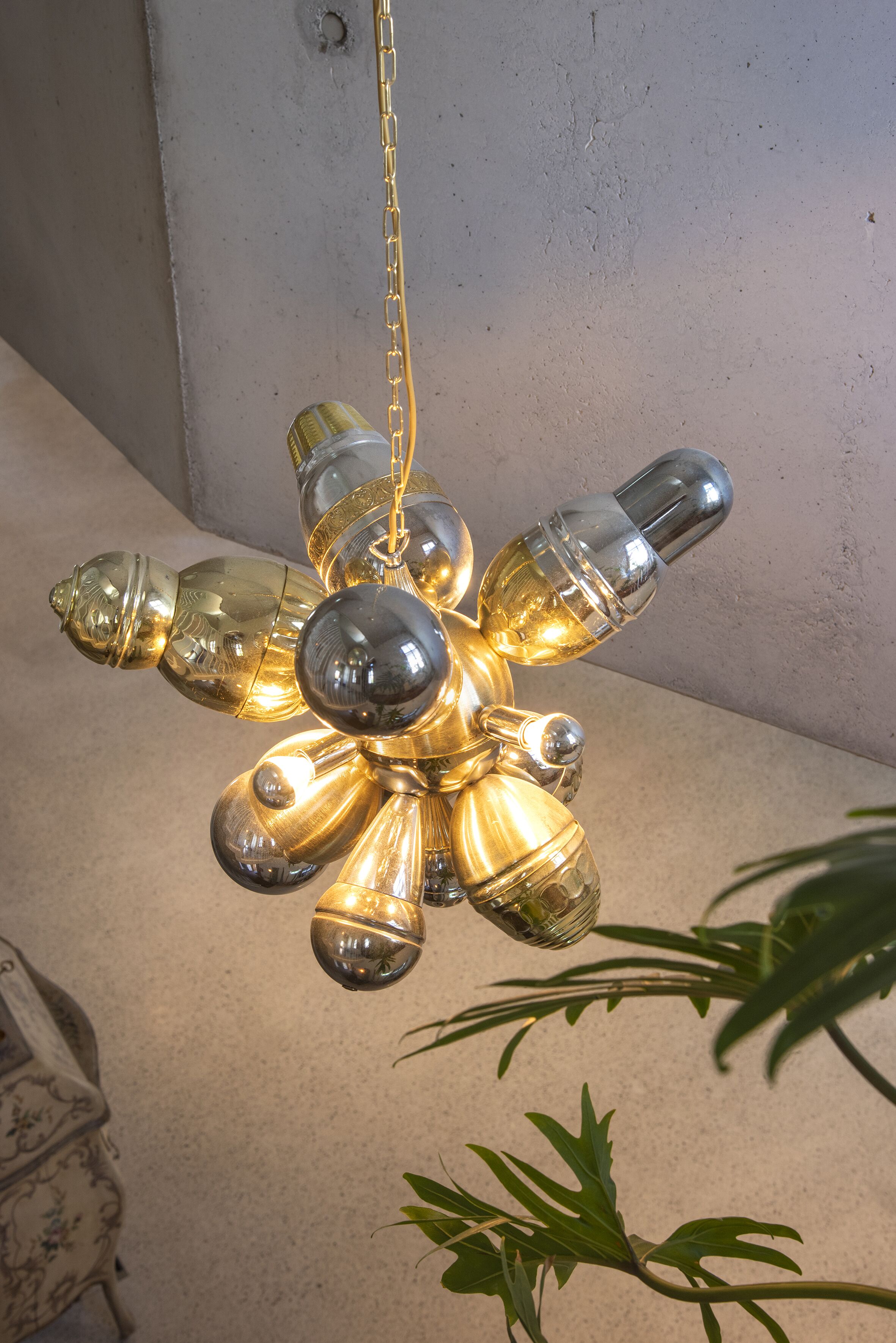 Um candelabro com várias lâmpadas de vidro e detalhes metálicos, suspenso por uma corrente.