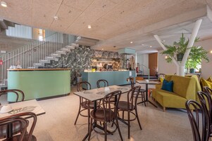 Um interior moderno com uma escada, uma área de refeições com mesa e cadeiras, um sofá e uma cozinha.