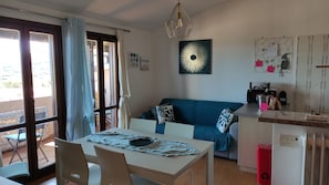 Um espaço compacto com área de jantar, cozinha compacta e sofá.