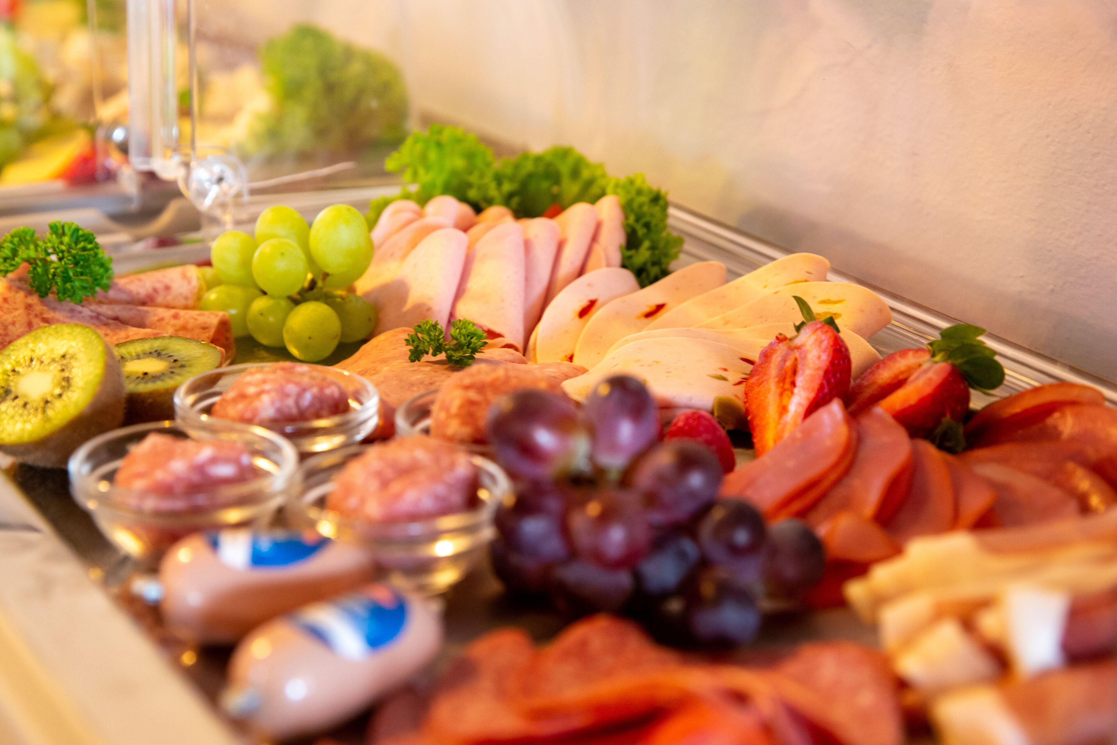 Tábua de frios com diversos queijos, carnes, frutas e pequenos recipientes com patês.