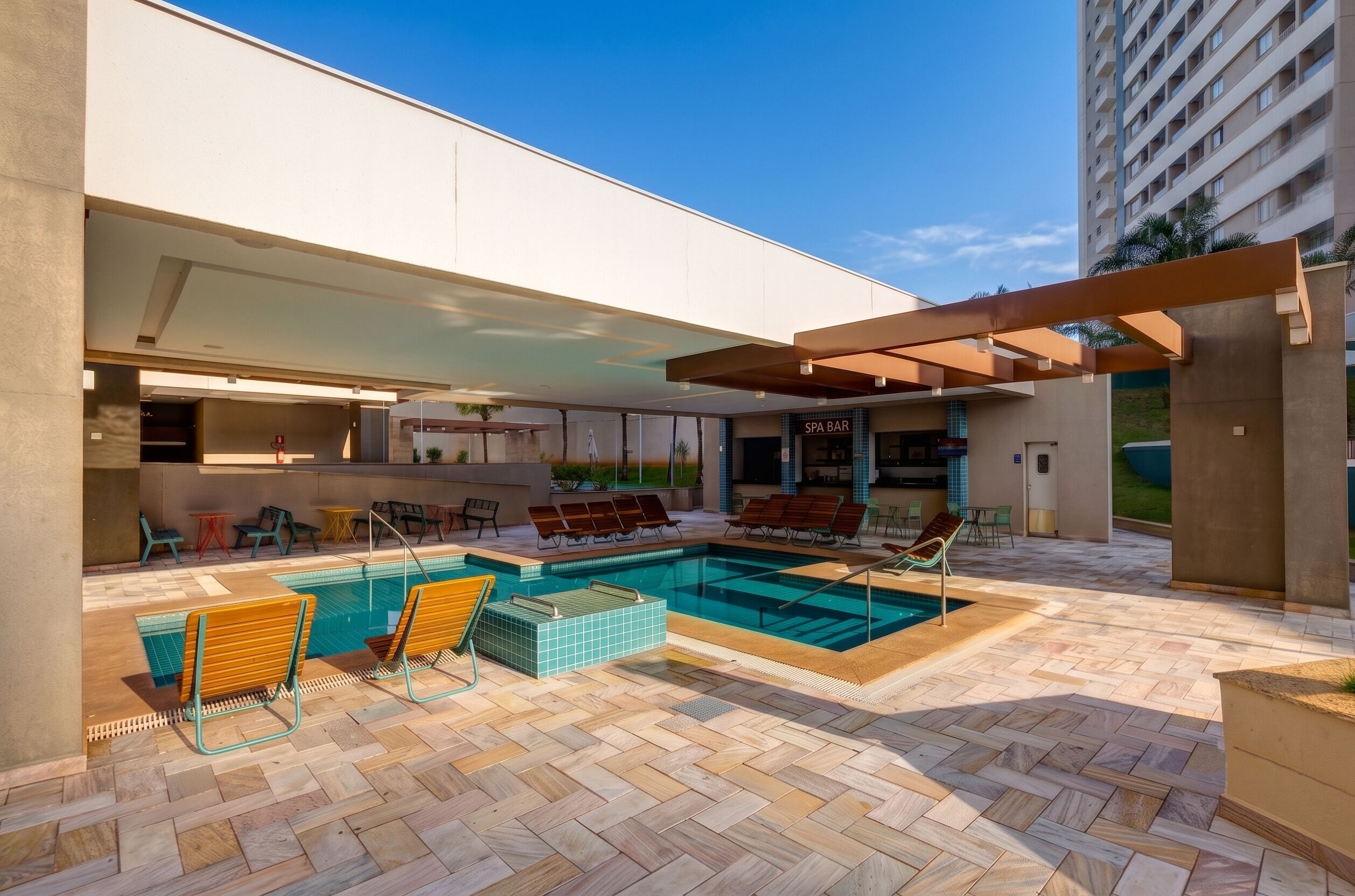 Uma área de piscina no terraço com espreguiçadeiras e um bar.