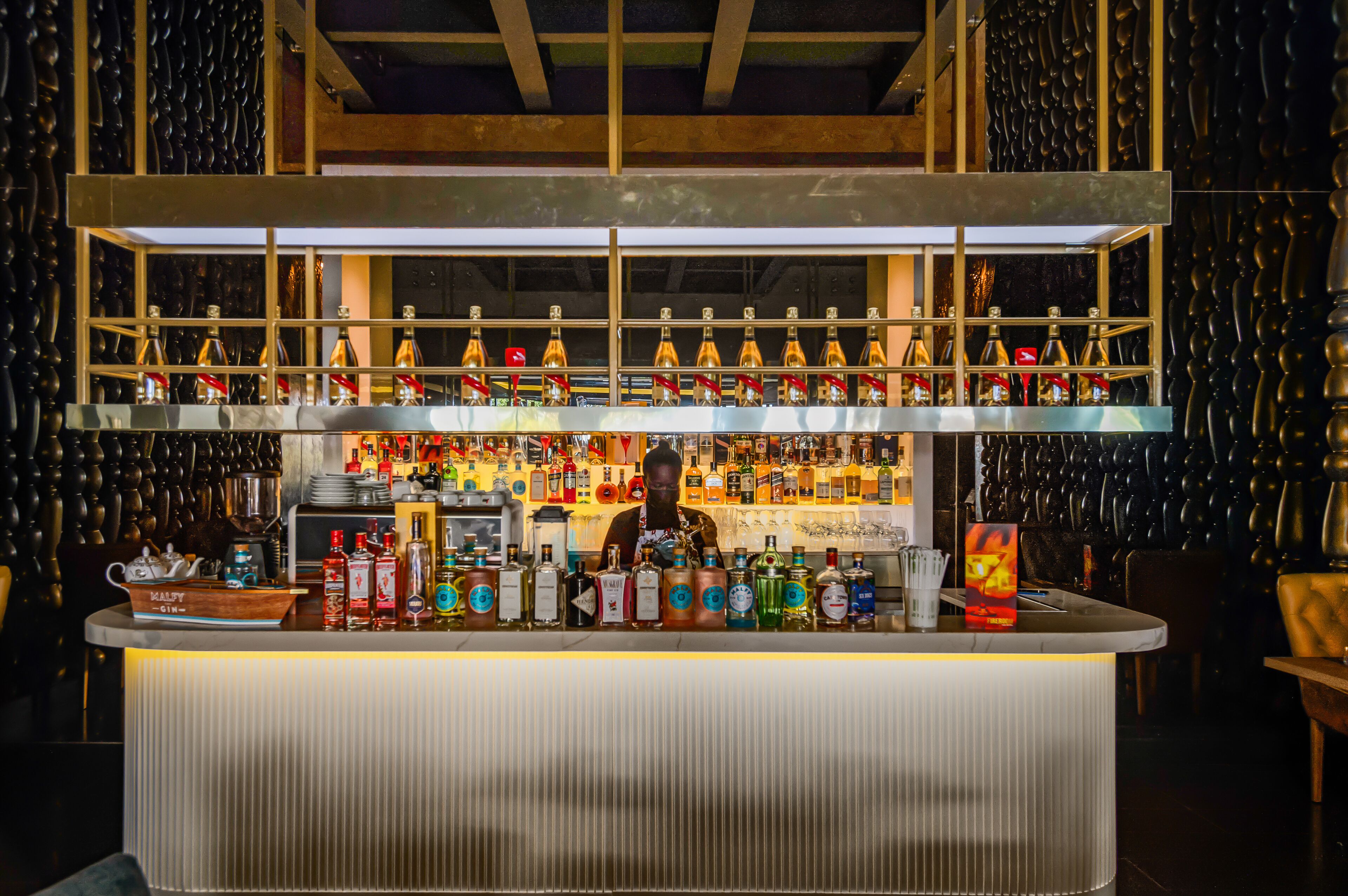 Um balcão de bar com várias prateleiras de garrafas e um bartender.