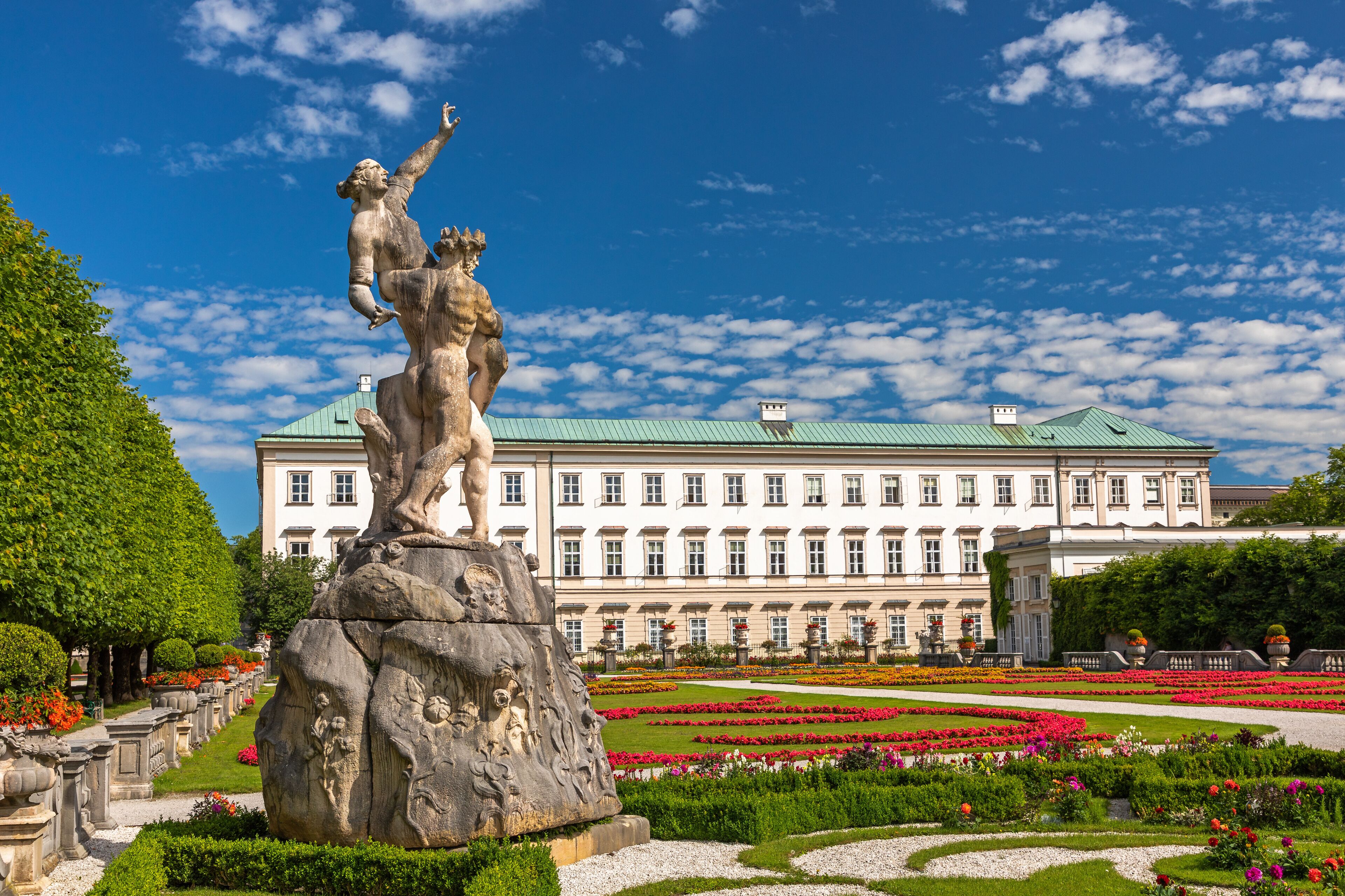 Um edifício grande com fachada simétrica e uma estátua em frente.