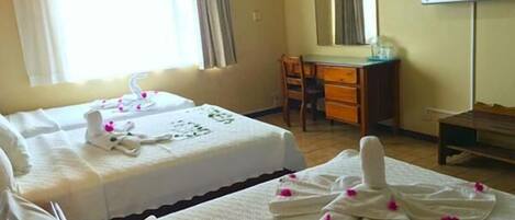 Quarto de hotel com duas camas, uma escrivaninha, uma cadeira, uma televisão e um espelho.