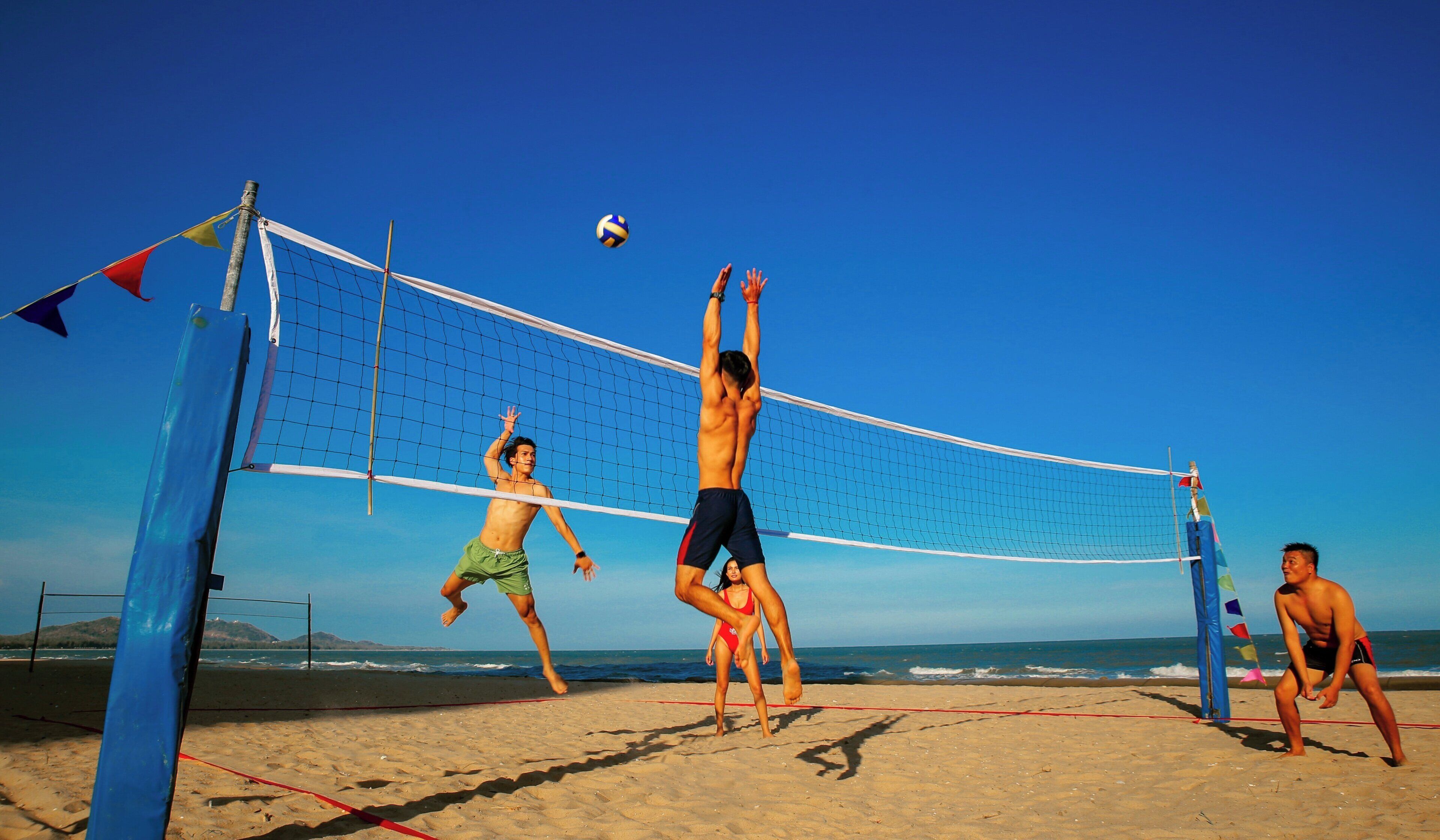 Jogo de voleibol de praia com rede e jogadores.