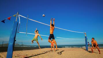 Jogo de voleibol de praia com rede e jogadores.