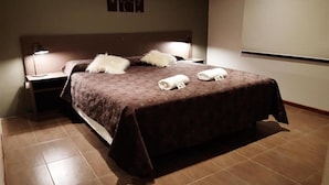 Uma cama bem arrumada com um espalha cama marrom estampado, dois travesseiros brancos e fofos, e duas toalhas dobradas sobre a cama.