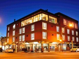 Um hotel com vários andares, restaurante no térreo e entrada visível.
