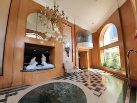 Um hall imponente com um lustre, piso de mármore e uma estátua de um cavalo.