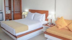 Quarto de hotel com cama, mesas de cabeceira, escrivaninha e guarda-roupa.