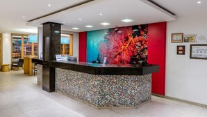 Uma área de recepção com balcão revestido de azulejos, um grande mural de recife de coral e certificados emoldurados na parede.