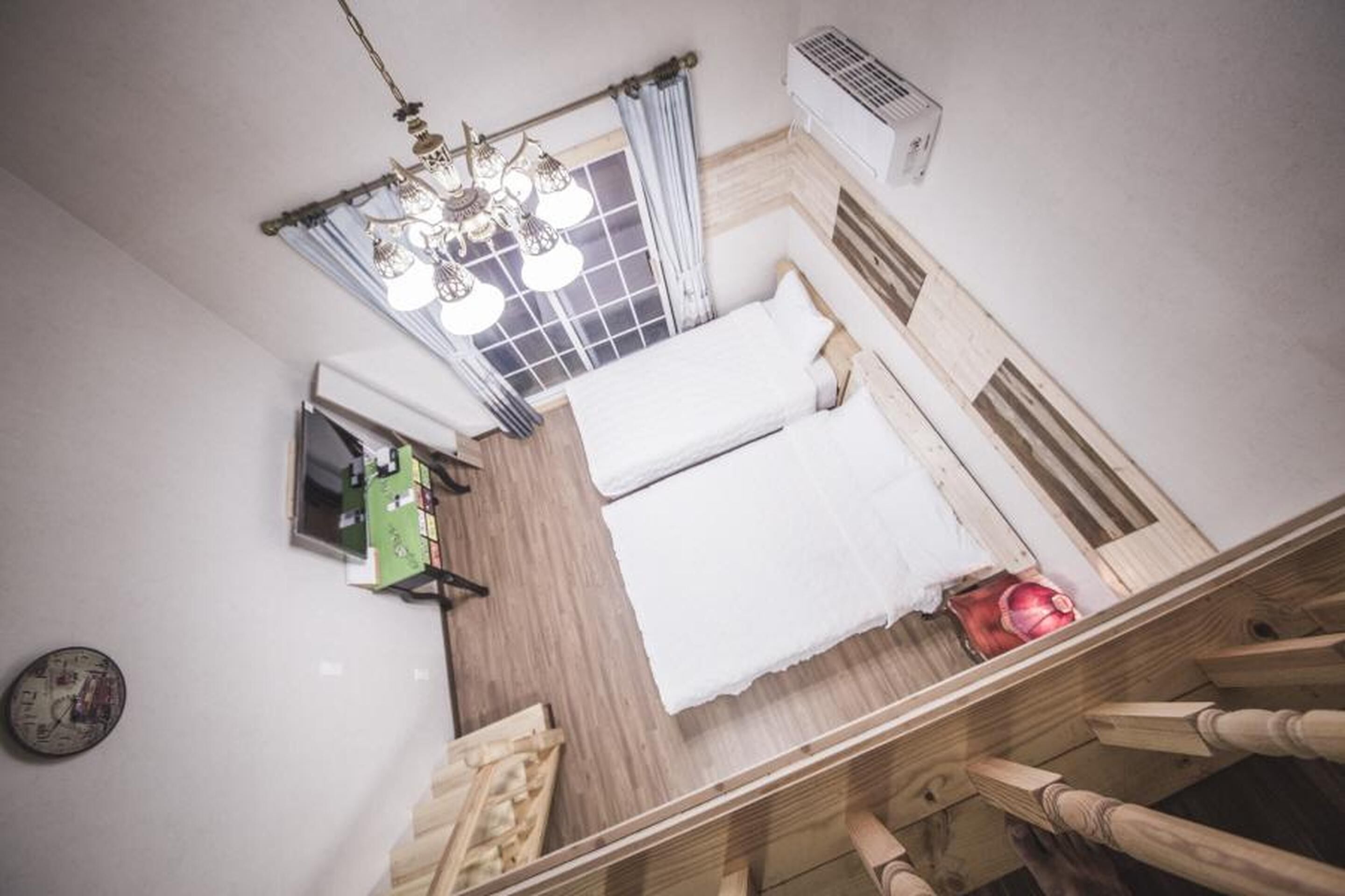 Um quarto com cama, janela com cortinas, lustre e ar condicionado fixado na parede.