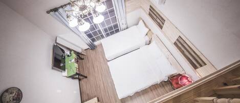 Um quarto com cama, janela com cortinas, lustre e ar condicionado fixado na parede.