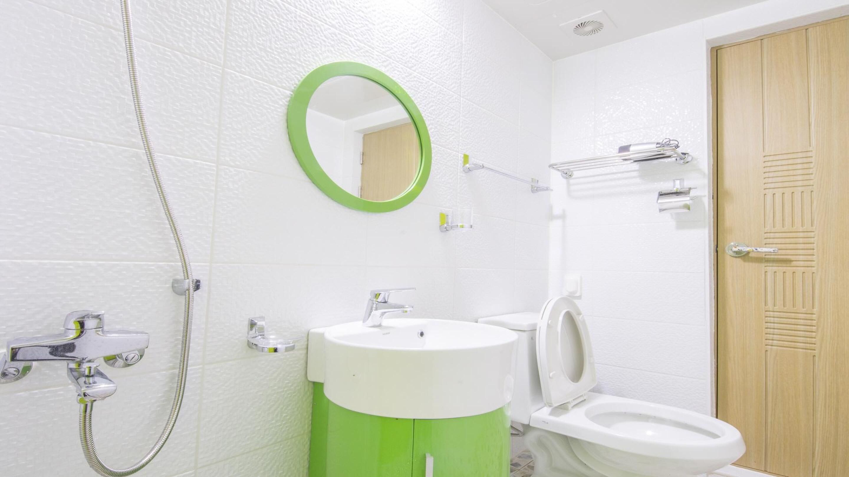 Casa de banho com lavatório branco, armário verde e sanita.