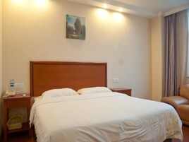 Quarto de hotel com uma cama grande, mesa de cabeceira, abajur e um quadro na parede.