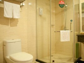 Casa de banho com chuveiro em cabine de vidro, sanita e porta-toalhas.
