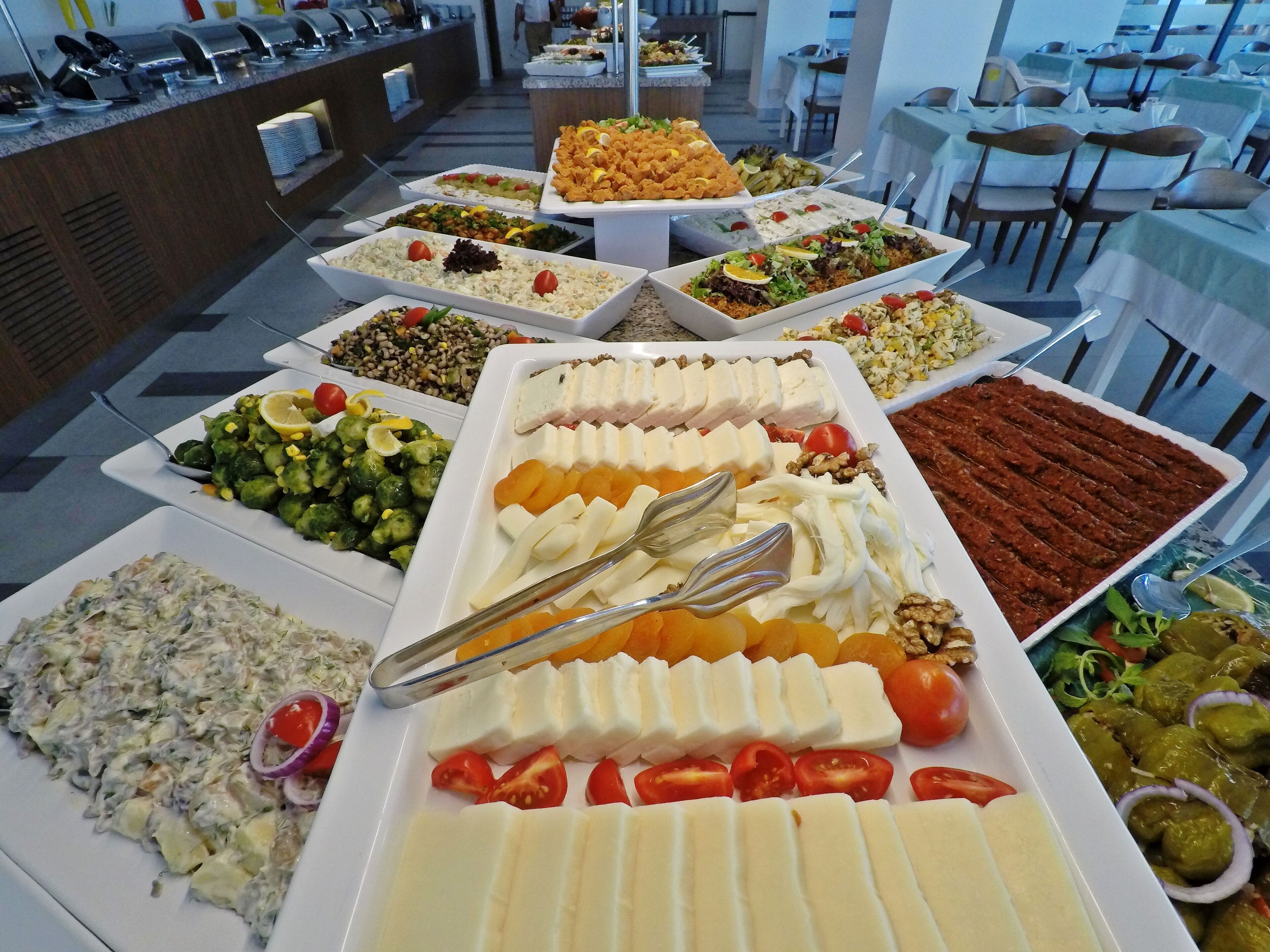 Buffet com diversas opções de comida, incluindo saladas, queijos e carnes.