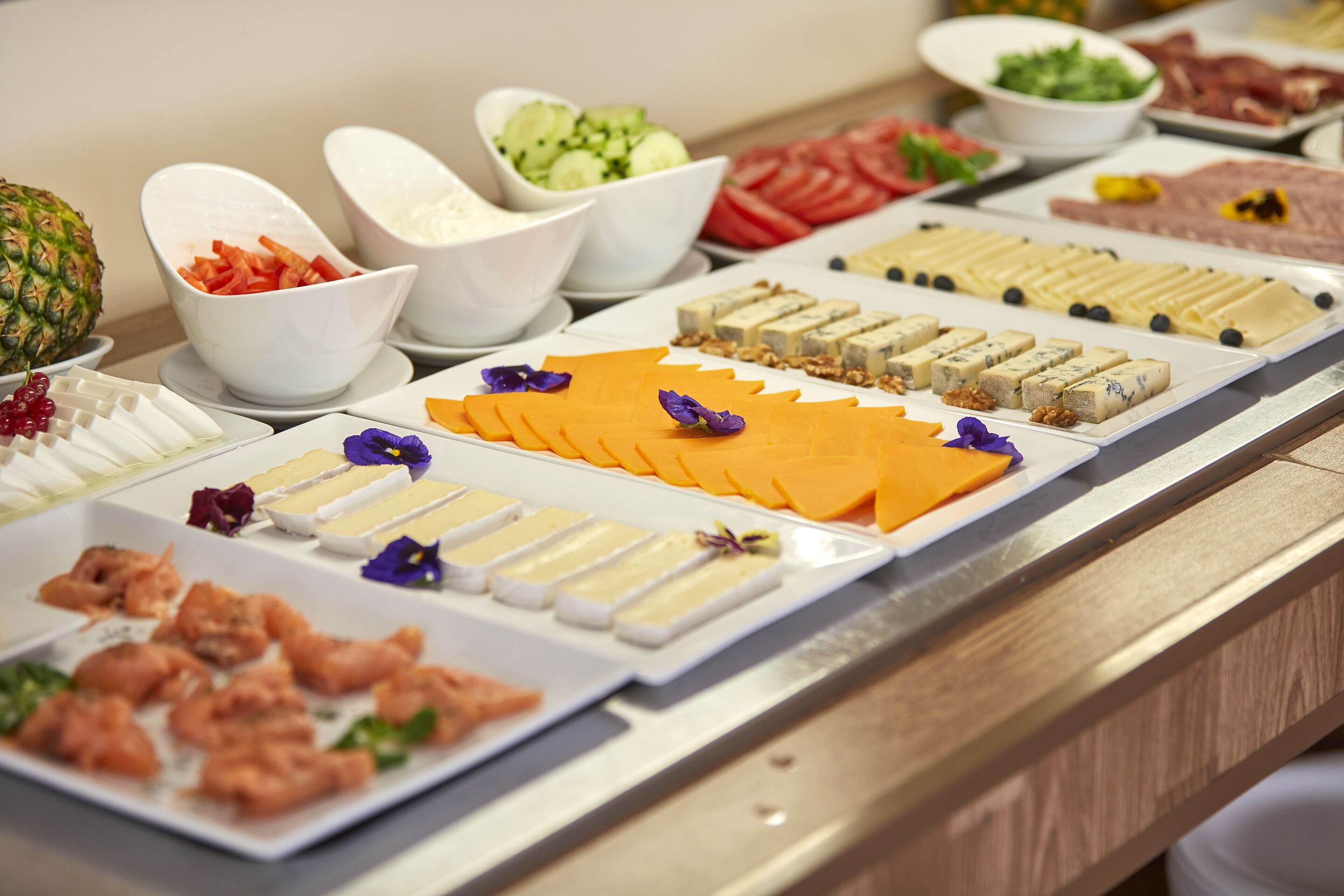 Buffet com diversos alimentos, incluindo frutas, queijos e carnes.