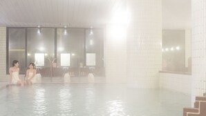Uma grande piscina interior com paredes em azulejo e teto com iluminação embutida.