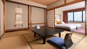 Quarto de hotel com piso de tatame, uma cama, uma mesa e vista para o exterior.