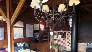 Um quarto amplo com vigas de madeira, um candelabro e obras de arte nas paredes.