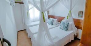 Quarto de hotel com duas camas de solteiro, cada uma com dossel e almofadas.