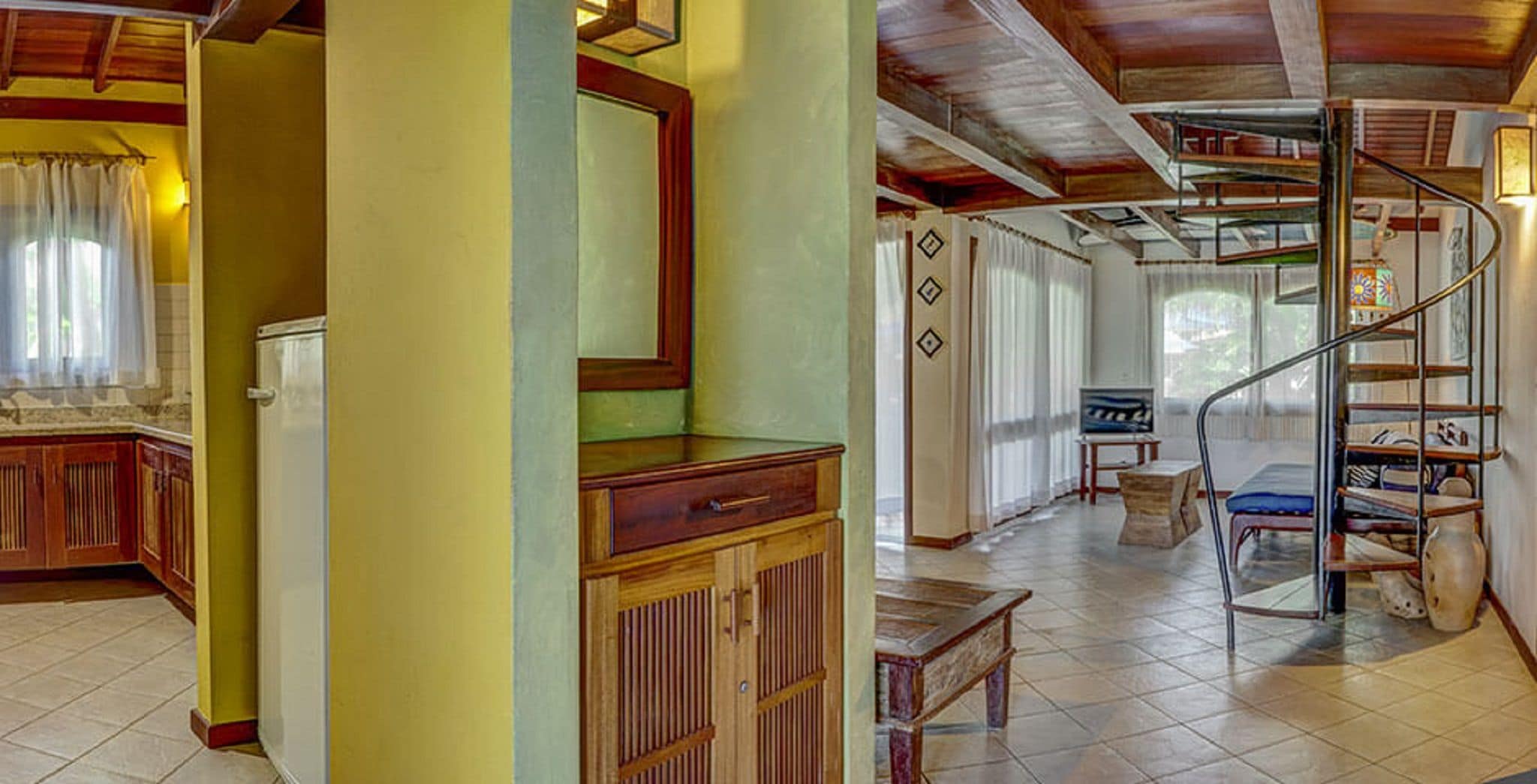 Uma sala de estar ampla, com cozinha, área de jantar e escada para um andar superior.