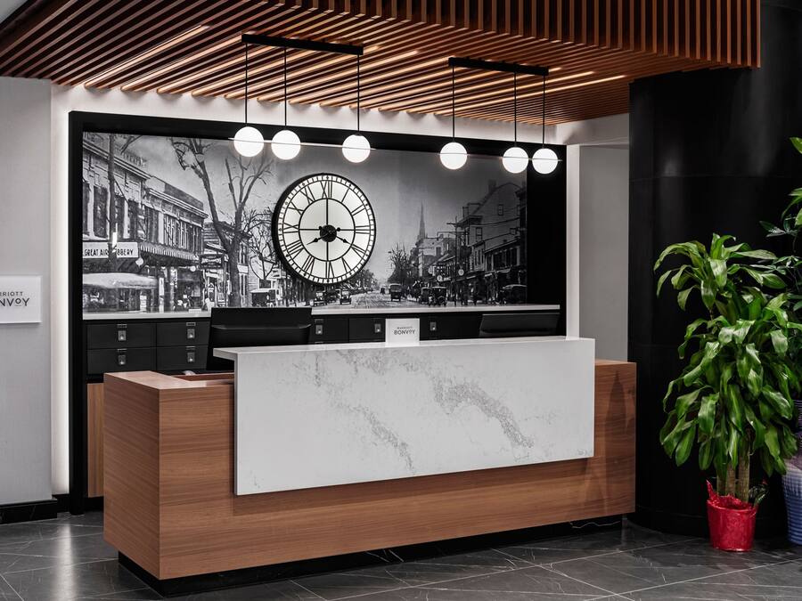 Uma receção com um relógio grande, um sinal de Marriott Bonvoy e uma planta em vaso.