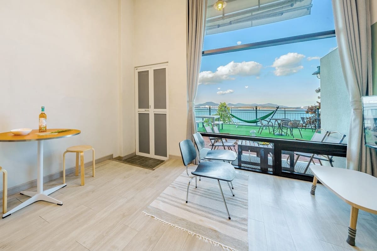 Quarto moderno com varanda, área de refeições e vista para uma paisagem verde.