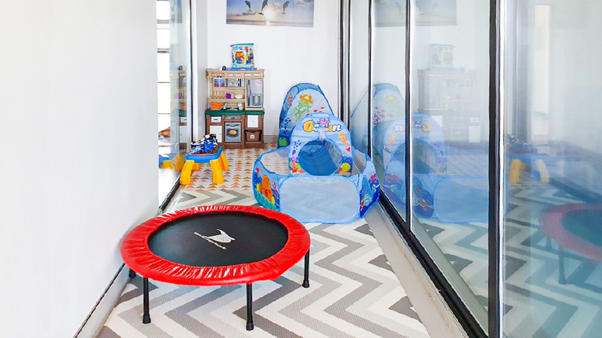 Quarto com trampolim, tenda de brincar e espaço infantil.