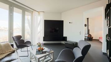 Uma sala de estar moderna com um sofá, poltronas, uma mesa de centro, uma televisão de tela plana e uma lareira.