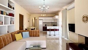 Uma sala de estar moderna com sofá, mesa de centro de vidro, televisão e estante.