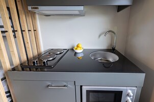 Minifrigorífico, uma placa de cozinha, utensílios de cozinha 