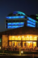 Um edifício com vários andares, varandas e um restaurante com mesas ao ar livre.